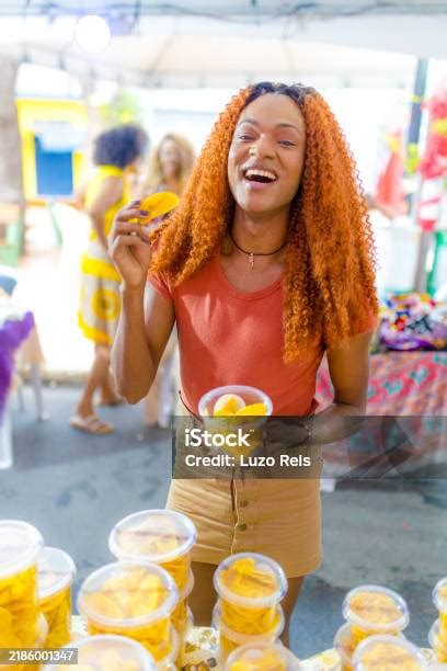 스트리트 마켓에서 바나나 칩을 먹으면서 미소를 지으며 카메라를 바라보는 여자 25 29세에 대한 스톡 사진 및 기타 이미지 25 29세 Lgbtqia 문화 건강한