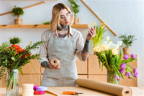 직장에서 꽃과 함께 노력 하 고 밧줄을 들고 안경에 아름 다운 젊은 플로리스트 갈색 용지에 대한 스톡 사진 및 기타 이미지 갈색 용지 기업가 꽃 식물 Istock