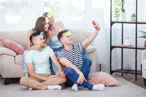 실내에서 셀카를 만드는 젊은 사람들 스마트 폰에 총을 만드는 친구의 그룹 자신의 사진을 찍는 사람들 프리미엄 사진
