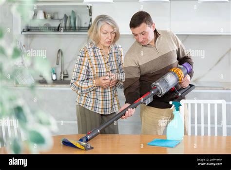 Male Salesman Tells An Elderly Woman How To Use New Cordless Vacuum