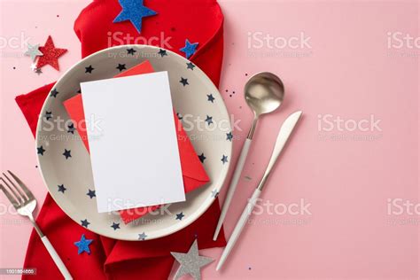미국 독립기념일을 위한 애국적인 파티 테이블 세팅의 평면도 접시 숟가락 포크 나이프 냅킨 엽서 봉투 반짝이는 별들이 파스텔 핑크 배경에 텍스트를 위한 빈 공간이 있다 0명에