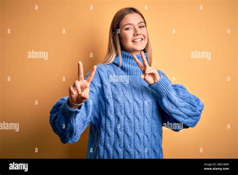 Young Beautiful Blonde Woman Wearing Turtleneck Sweater Over Yellow