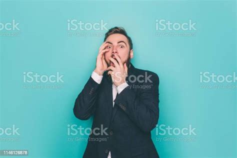 젊은 남자의 수평 사진입니다 그는 무서 워 서 겁에 질린 다 남자는 자신의 손으로 얼굴의 부분을 폐쇄 했다 파란색 배경에