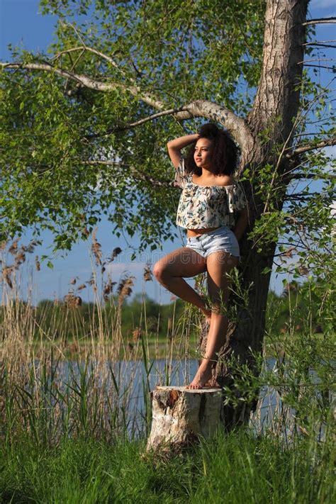 Beautiful African Woman With Curly Hair Standing At A Tree Stock Image