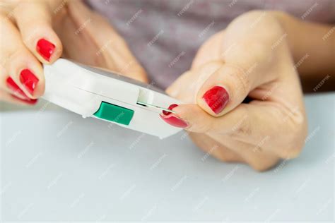 Premium Photo Close Up Of Hand Holding Glucometer On Table