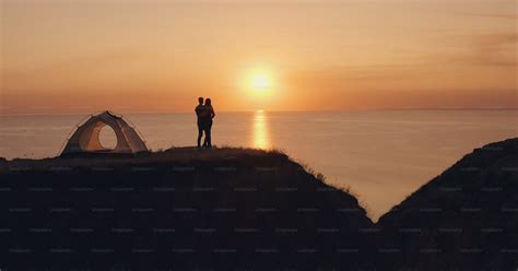 바닷가의 캠프장 텐트 근처에 서 있는 남자와 여자 사진 Unsplash의 태양 이미지