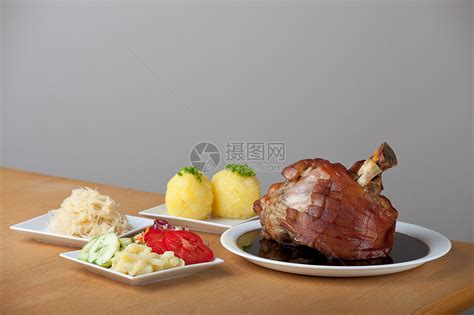 木制桌上的烤猪肉桌子蔬菜饺子酸菜盘子肉汁猪肉烹饪沙拉斧头高清图片下载 正版图片320343531 摄图网