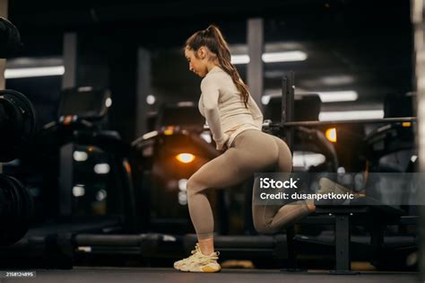 체육관의 벤치에서 스플릿 스쿼트 운동을 하는 건강한 스포츠 여성의 측면 모습 Practice Round에 대한 스톡 사진 및