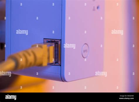 WiFi Extender In Electrical Socket On The Wall With Ethernet Cable Plugged In The Device Is In