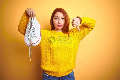 年轻漂亮的红发女人拿着白色运动鞋高清图片下载 正版图片504529540 摄图网