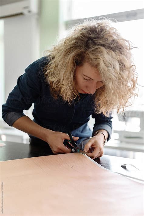 Woman Cutting Sewing Pattern From Paper By Stocksy Contributor