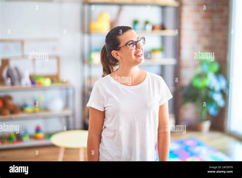 Young Beautiful Teacher Wearing Glasses Standing At Kindergarten Stock