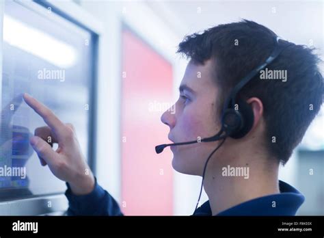 Side View Of Young Man Wearing Headset Using Touch Screen Computer