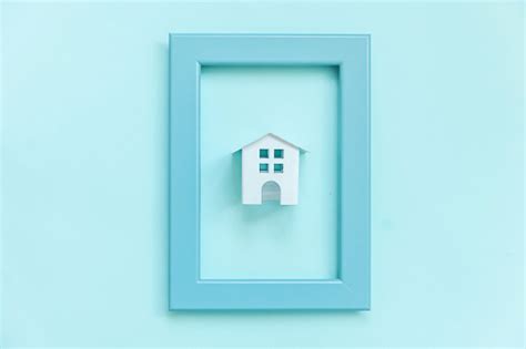 블루 파스텔 컬러의 트렌디 한 배경에 고립 된 파란색 프레임의 미니어처 흰색 장난감 집으로 간단하게 디자인 개념에 대한 스톡