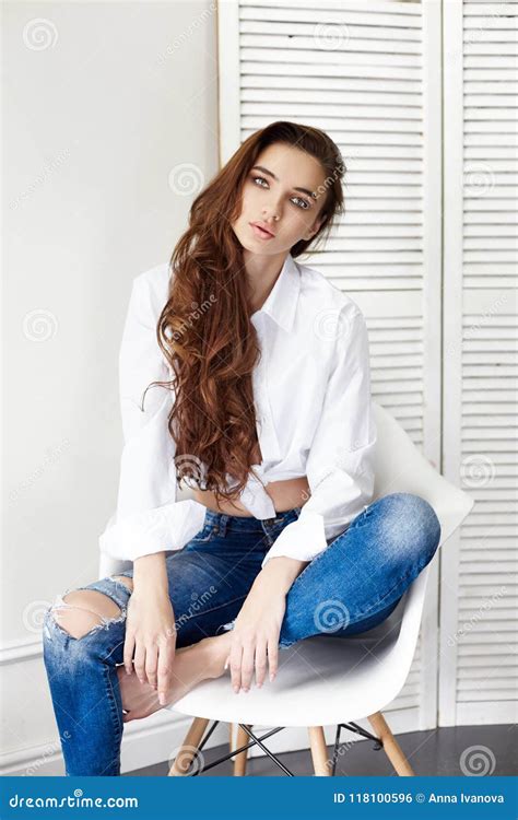 Bella Ragazza Sexy In Camicia Bianca Dei Jeans Che Si Siede Su Una