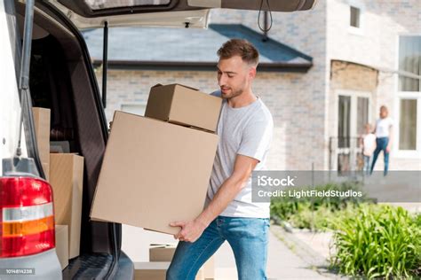 그의 아내와 딸 새로운 별장 근처에 서 있는 동안 이전에 대 한 골 판지 상자를 들고 하는 남자 이주 개념에 대한 스톡 사진 및 기타 이미지 Istock