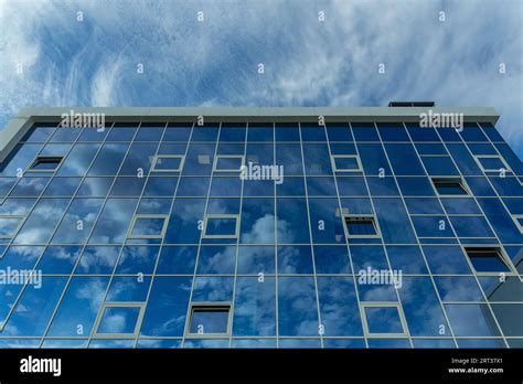Architectural Detail Of The Facade With Multiple Reflections Of Cloudy Sky And The Sun Exterior