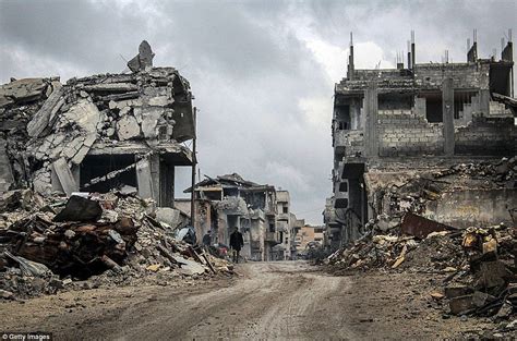 A Dirt Road Surrounded By Destroyed Buildings And Rubble On Both Sides