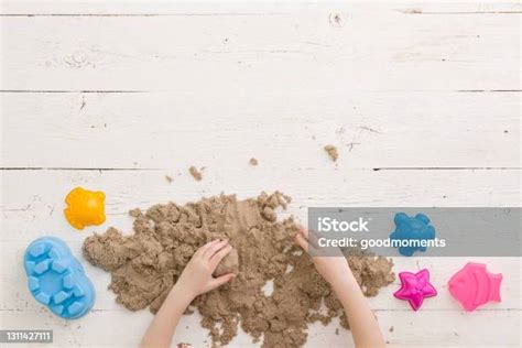 흰색 나무 테이블 배경에 운동 모래와 주석을 가지고 노는 아이의 손에 상단 보기 재생하여 학습 개념에 대한 스톡 사진 및 기타