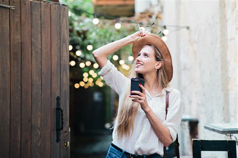 이동 중커피 한 잔과 함께 구시 가지의 거리를 따라 걷는 캐주얼 스타일의 옷을 입은 젊은 매력적인 여성 갈란드 장식품에 대한 스톡 사진 및 기타 이미지 Istock