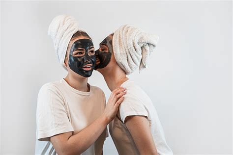 흰 티셔츠를 입은 두 명의 여자 친구 또는 자매와 머리에 수건을 씌운 클레이 마스크를 착용하고 격리 2명에 대한 스톡 사진 및