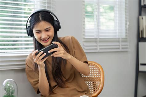 밝고 현대적인 가정 환경에서 스마트 폰과 헤드폰으로 현대 기술 라이프 스타일을 즐기는 젊은 여성 Youth Organization에 대한 스톡 사진 및 기타 이미지 Istock