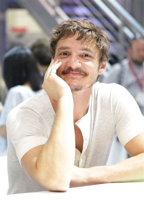 A Man Sitting At A Table With His Chin Resting On His Hand And Looking