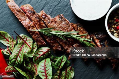 얇게 썬 구운 스테이크 중간 희귀 야채와 함께 블랙 커팅 보드에 제공됩니다 Steakhouse에 대한 스톡 사진 및 기타 이미지 Steakhouse 건강한 식생활