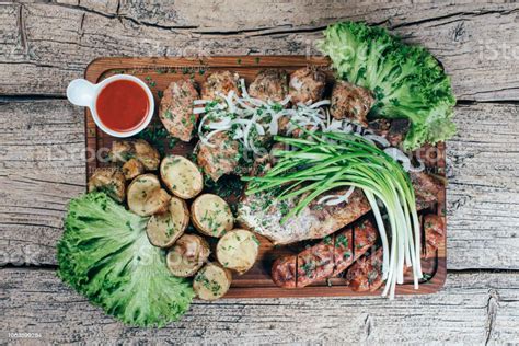 그린 샐러드와 토마토 소스와 감자의 잎과 함께 나무 보드에 석쇠에 식욕을 돋 우는 볶은 돼지고기 조각 갈색에 대한 스톡 사진 및