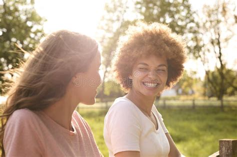 Two Female Friends Or Same Sex Couple Leaning On Fence On Walk In