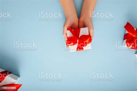 파란색 배경에 빨간 리본 리본이 달린 흰색 선물 상자를 들고 있는 어린이의 손 공휴일에 대한 스톡 사진 및 기타 이미지