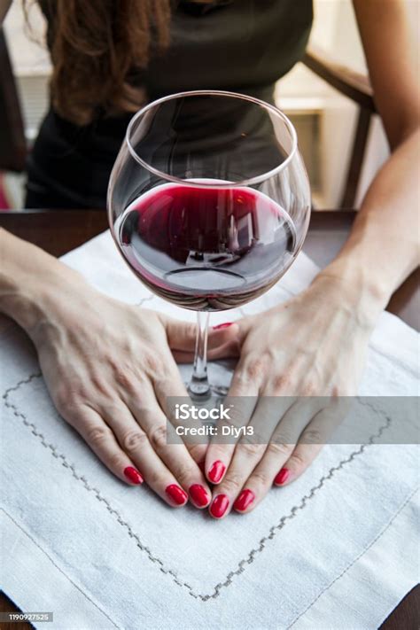 빨간 손톱을 가진 여자의 손은 레스토랑의 테이블에 흰색 냅킨에 레드 와인 레드 와인의 큰 유리와 잔 잔을 보유하고있다 붉은 포도주에 대한 스톡 사진 및 기타 이미지 Istock