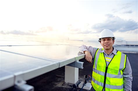 자랑스러운 젊은 엔지니어의 초상화는 지붕 재생 에너지 기술 전기 서비스 녹색 전력에 대한 그의 성공적인 작업에 만족미소를 짓습니다 설치에 대한 스톡 사진 및 기타 이미지
