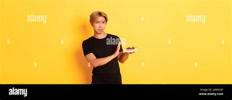 Portrait Of Disgusted And Upset Young Asian Guy Refuse Eating Cake