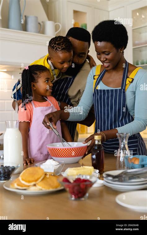 African American Father With Son And Daughter Looking At Mother Mixing