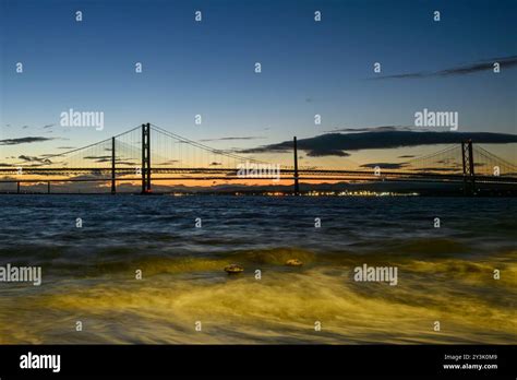 A View Of The Forth Rail Bridge Against A Sunset Sky With The Queensferry Crossing Bridge In The
