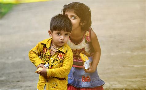 노란색과 빨간색 꽃무늬 긴 소매 셔츠를 입은 소녀가 파란색 플라스틱 병을 들고 있다 사진 Unsplash의 무료 의복 이미지