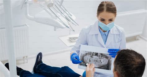 치아 염증 전문 숙련 된 여성 치과 의사가 Xray 사진을 들고 진단을 설명하면서 환자를 바라보고 있습니다 사진 Unsplash의 병원 이미지