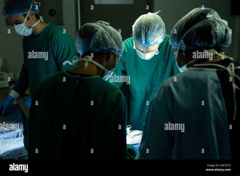 Diverse Group Of Female And Male Surgeons Operating On Patient In Operating Theatre Stock Photo