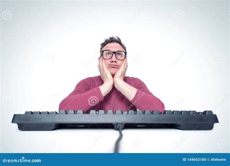 Thinking Man In Glasses Behind A Keyboard In Front Of A Computer