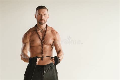A Man With A Naked Torso Is Engaged In Strength Fitness Using A Rubber