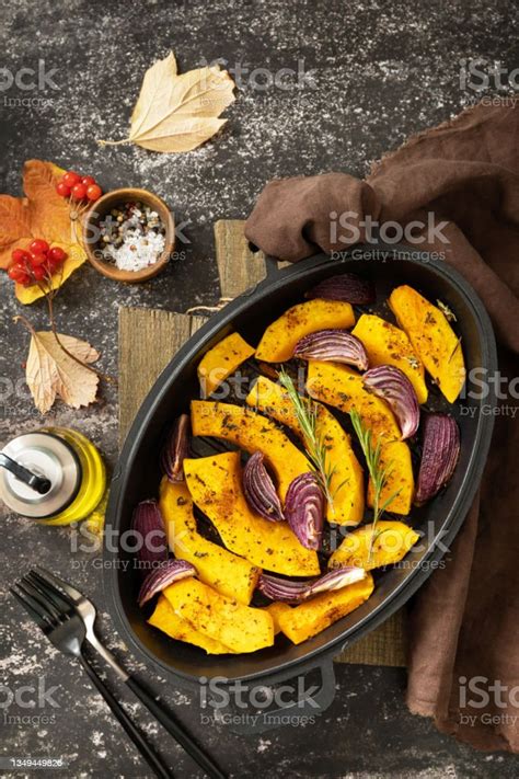 호박은 로즈마리와 보라색 양파로 슬라이스하고 어두운 돌 배경에 향신료로 신선한 건강한 음식을 굽습니다 케토 또는 팔레오 다이어트