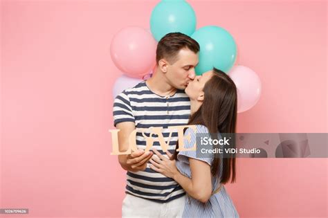 사랑에 행복 한 키스 하는 젊은 커플의 초상화입니다 여자의 남자 가슴 축 하 생일 휴일에 마른 파스텔 핑크 배경에 화려한 공기