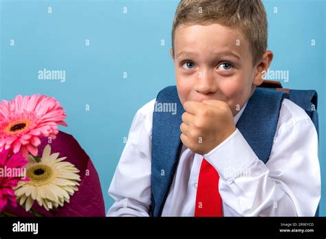 A Happy First Grader In A White Shirt Holds A Bouquet Of Flowers In His