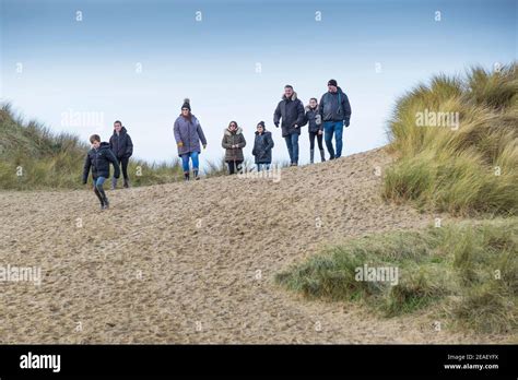 A Group Of People Walking On The Sand Dune System At Crantock Beach In