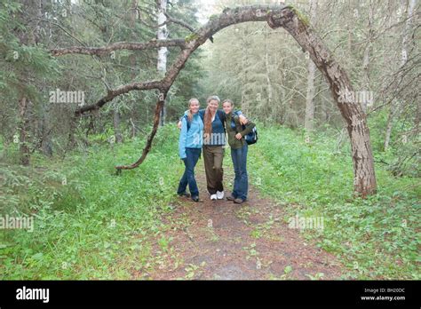 Woman And Two Girls On Hiking Trail Beside Tree Arched Over Trail Manitoba Canada Stock Photo