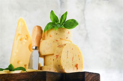 토마토와 조미료가 들어간 치즈와 스위스 치즈를 바질과 칼로 곁들인 치즈를 밝은 회색 테이블 배경에 보드에 올려 놓습니다 다른