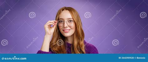 Cute Nerdy Female Student With Natural Beautiful Red Hair Touching Rim Of Glasses And Smiling