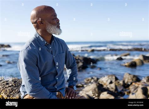 Thoughtful Senior African American Man Sitting On Rocks And Admiring