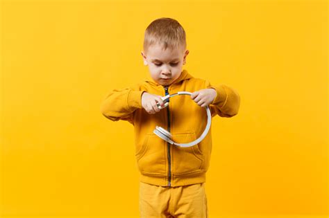 작은 아이가 소년 34 년 된 헤드폰에 노란색 옷을 입고 오렌지 벽 배경 어린이 스튜디오 초상화에 고립 사람들이 진심으 감정 어린 시절 라이프 스타일 개념 복사 공간을 모의